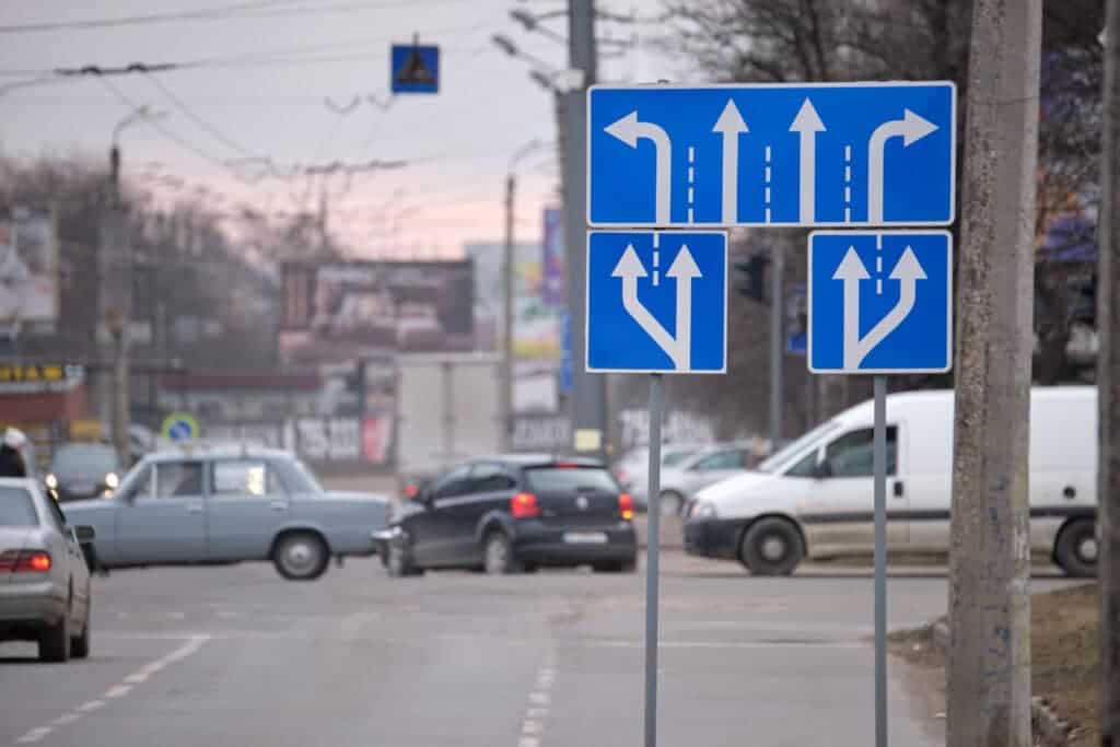 Traffic sign pointing multiple road lanes direction on city street ...